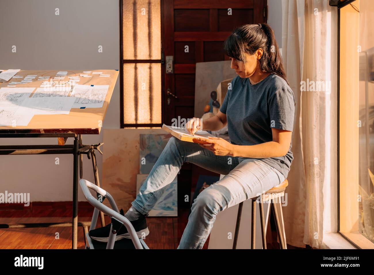 Side view of Woman at home relaxed drawing and painting close to the ...