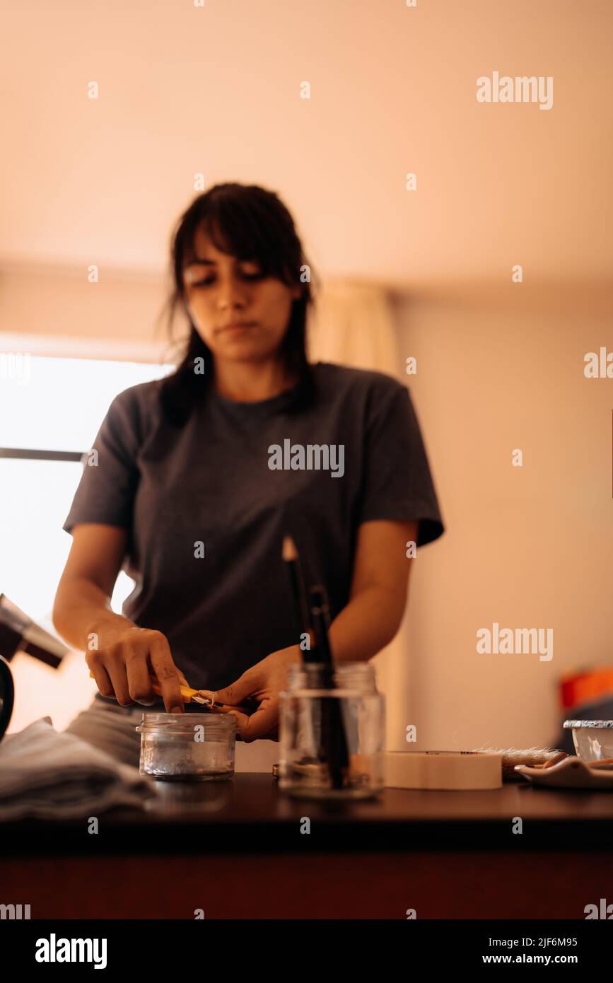 Latin Woman sharpening a pencil at home while drawing Stock Photo - Alamy