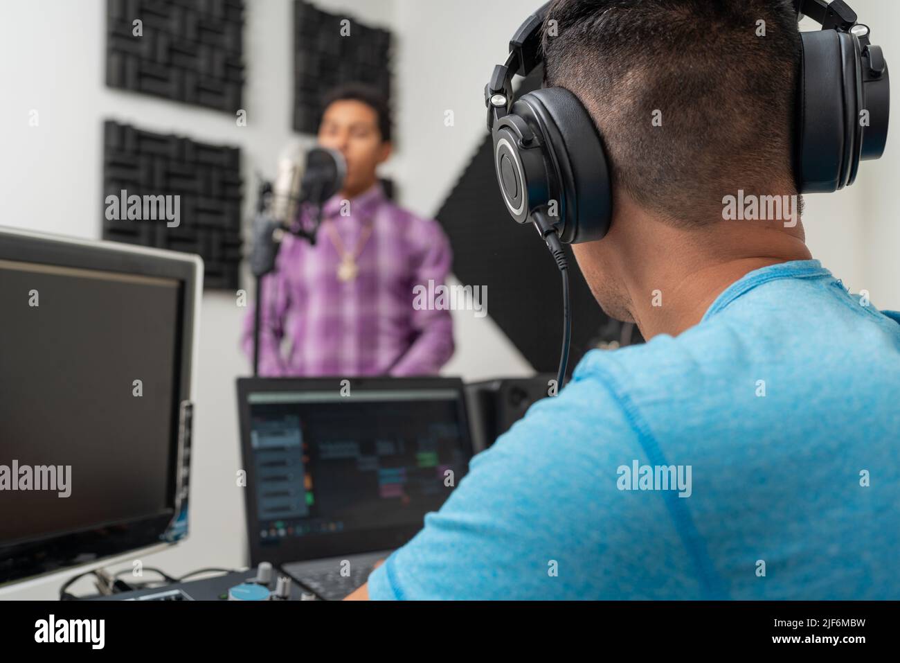 Young male singer recording voice in mic at music studio Stock Photo ...