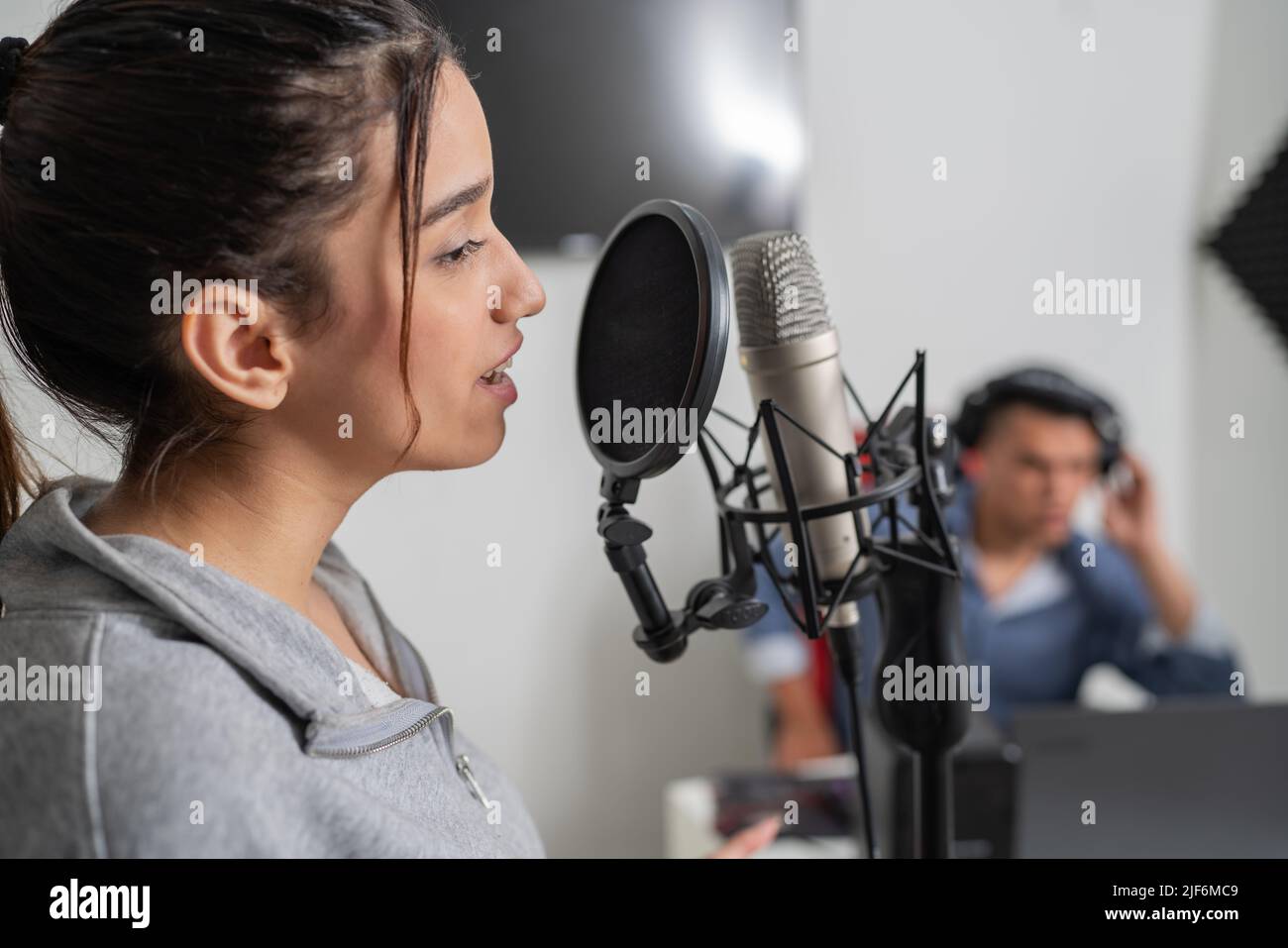 Young female singer recording voice in mic at music studio Stock Photo ...