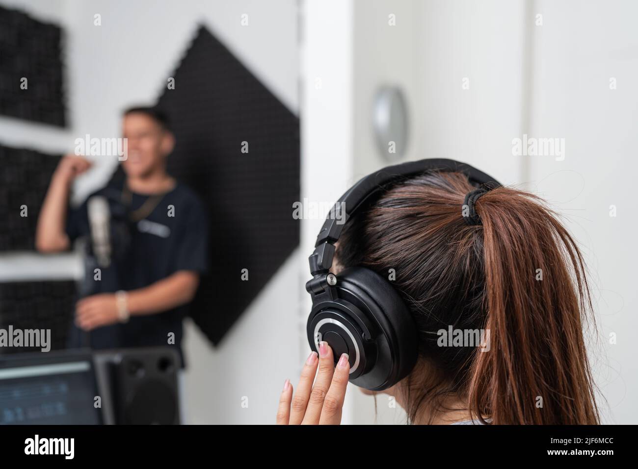 Young male artist singing in microphone while recording voice in music ...