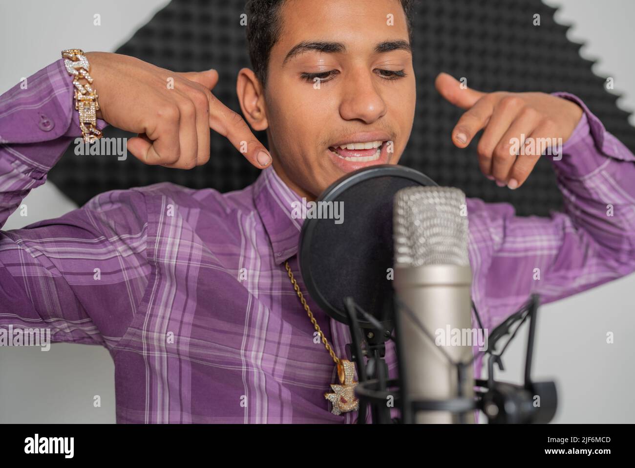 Young man singing in microphone while recording voice in music studio ...