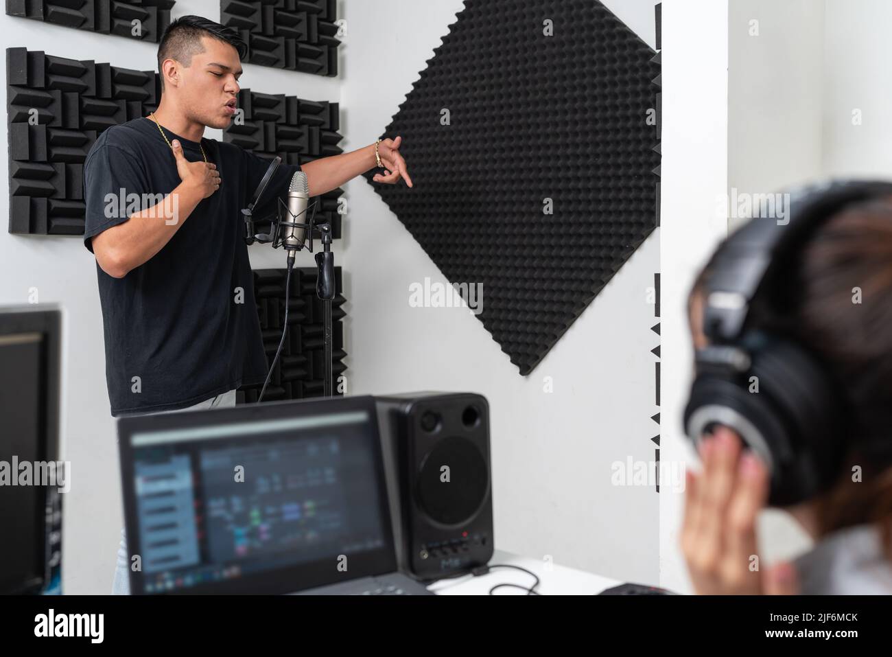 Young male artist singing in microphone while recording voice in music ...