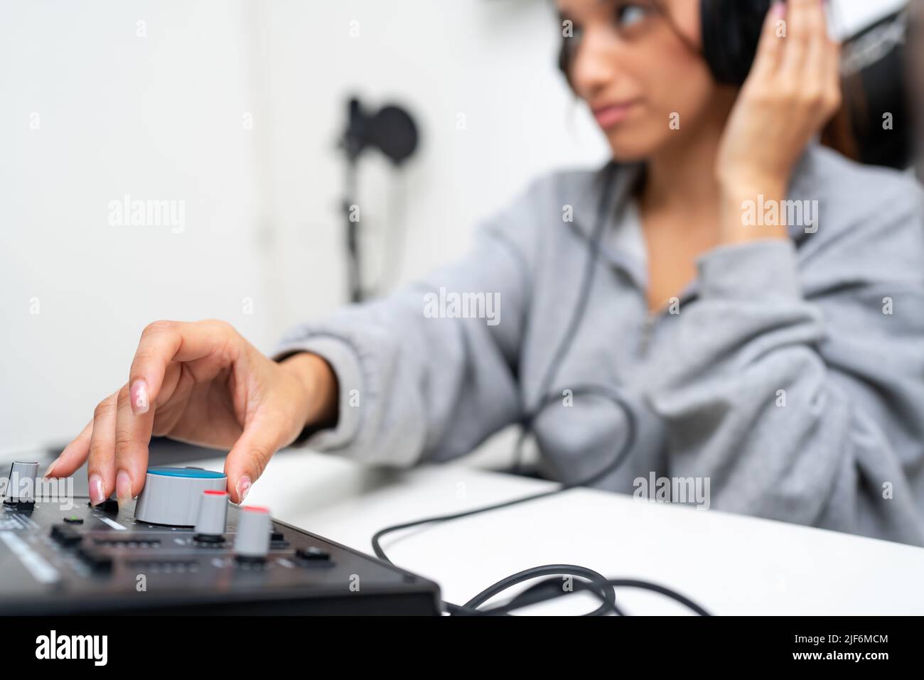 Female audio engineer fine tuning the sound on knob in recording studio ...
