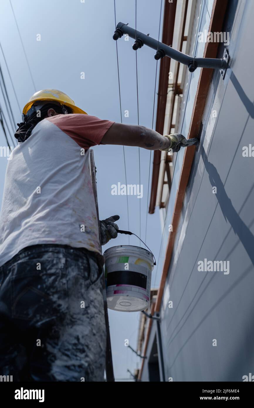 From below professional male painter in yellow hardhat in process of ...