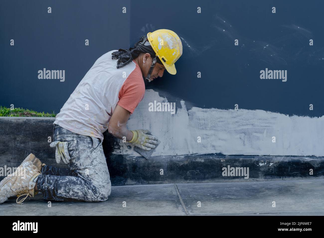 Side view of professional male painter in yellow hardhat in process of ...
