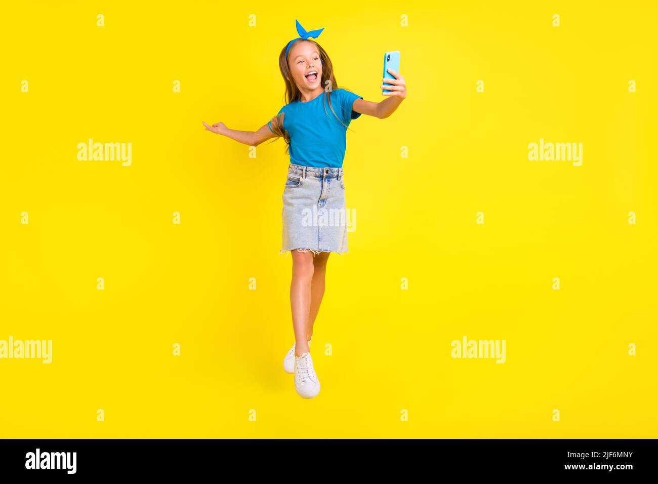 Full size photo of excited small girl jumping hold telephone make ...