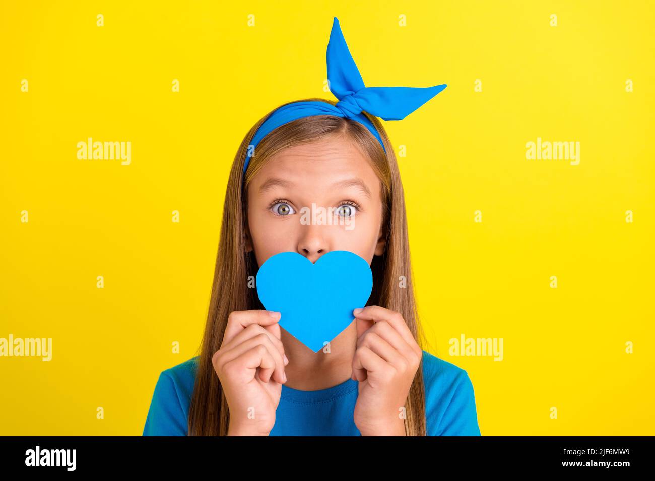 Portrait of impressed pupil arms hold paper heart card cover mouth ...