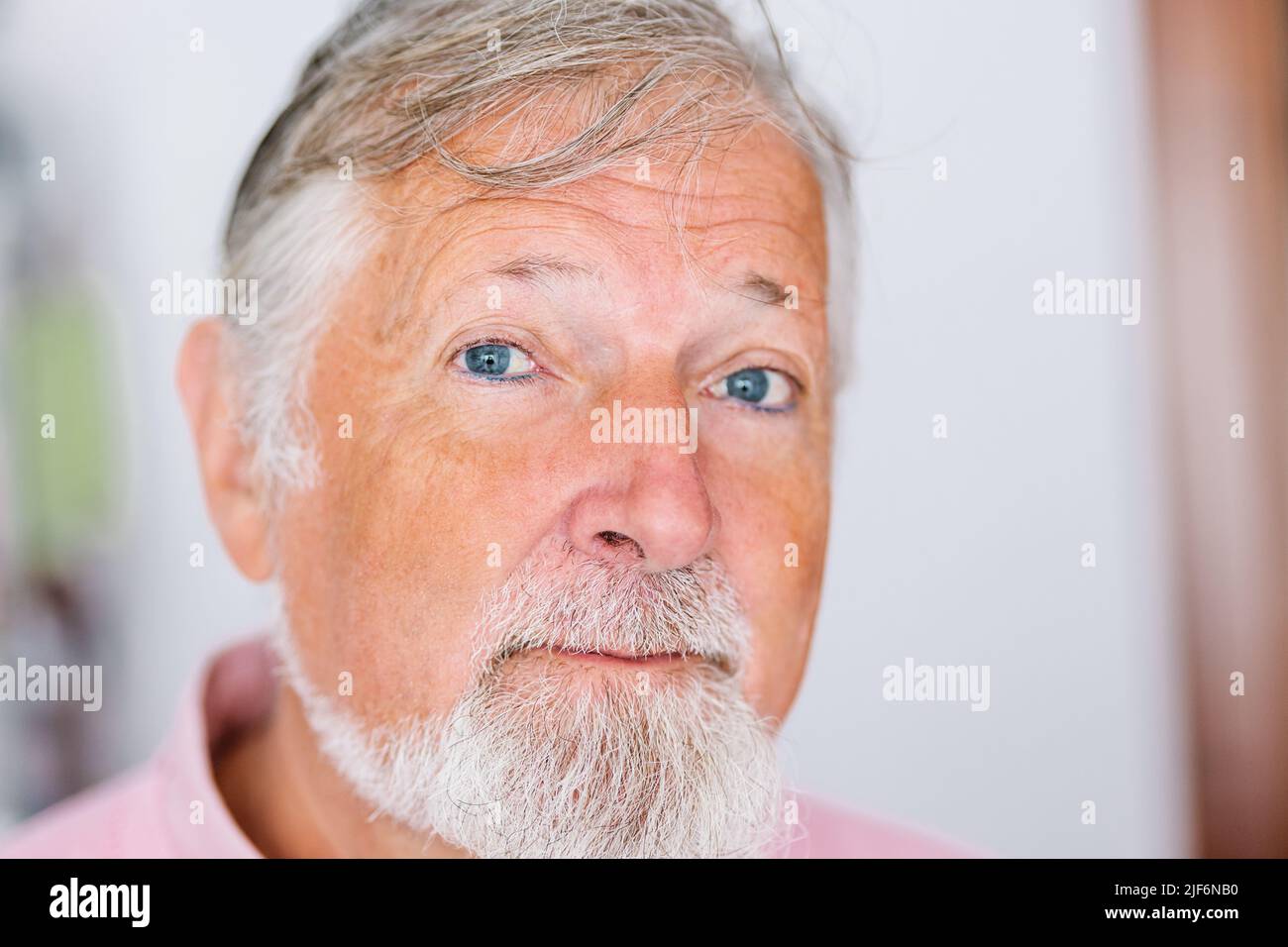 Headshot of elderly male with gray hair and beard looking at camera in ...