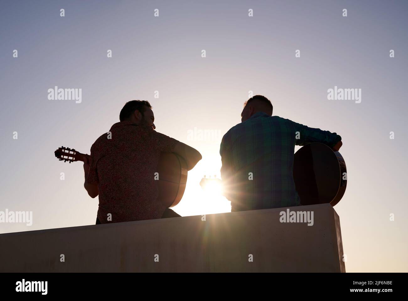Back view silhouette of anonymous male musicians playing song on ...