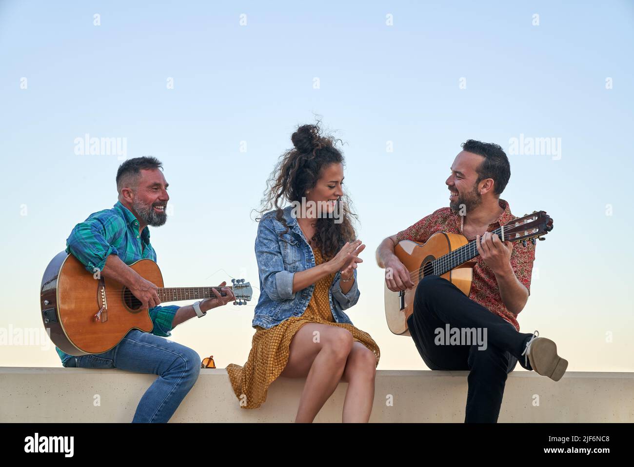 Content male musicians playing song on acoustic guitars near clapping ...