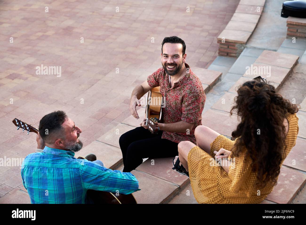 Content male musicians playing songs on acoustic guitars and looking at ...
