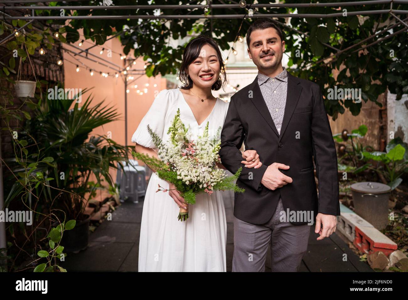 Loving Multiracial couple in wedding outfits smiling and looking at ...