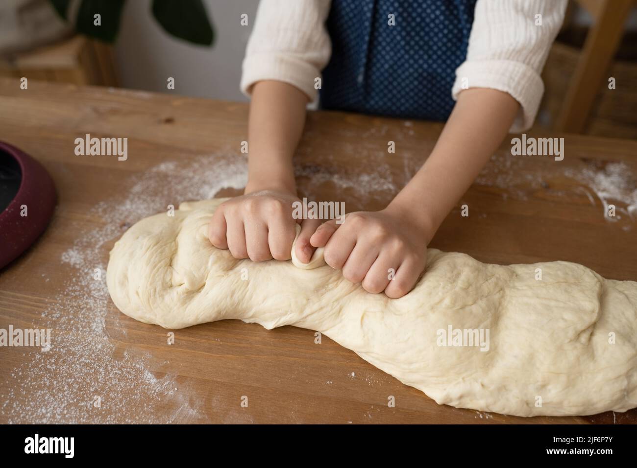 Anonymous Cute little girl kneading dough on wooden table at home Stock ...