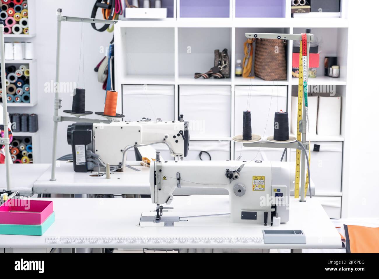 Professional sewing machines with spools of thread placed on white ...