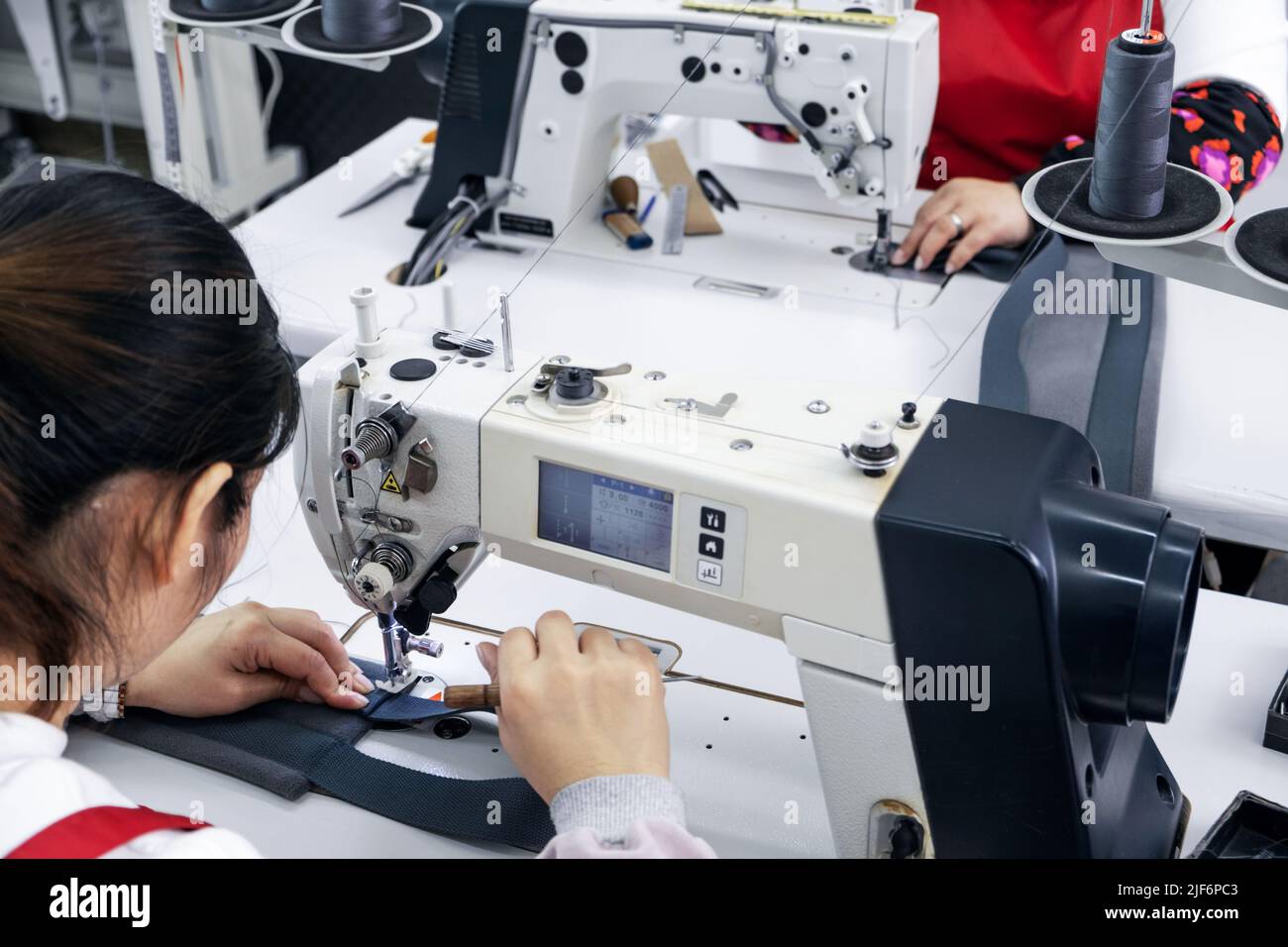 Anonymous cropped dressmakers in uniform sewing on machine while ...