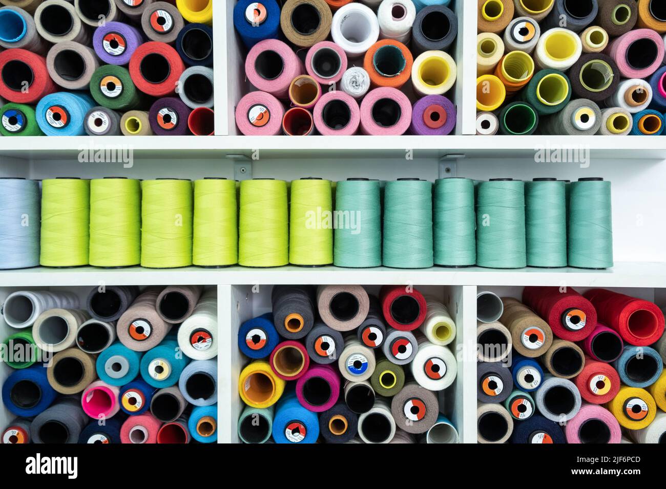 Set of colorful spools of threads for sewing stacked together on white ...