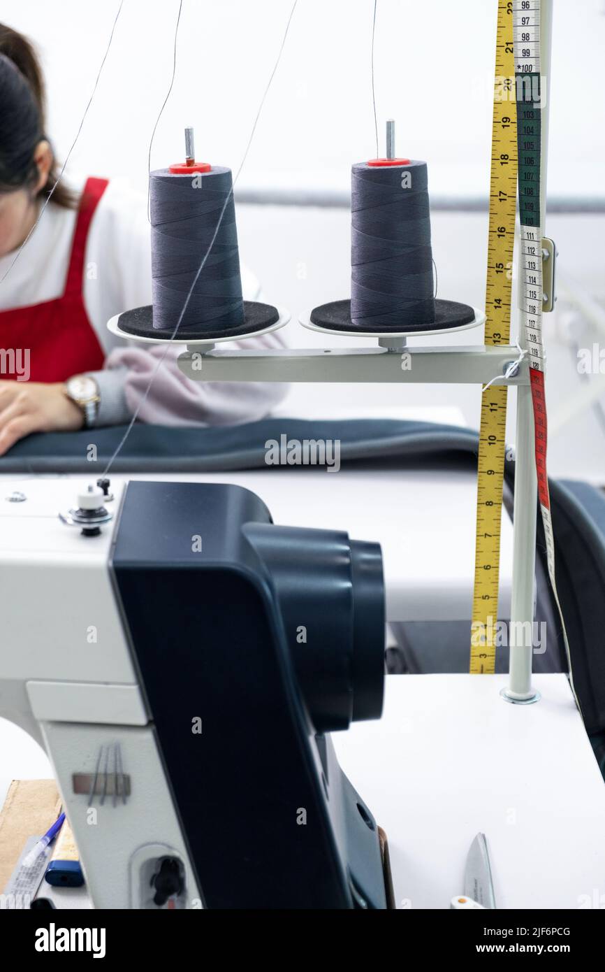Anonymous cropped dressmaker in uniform sewing on machine while working ...