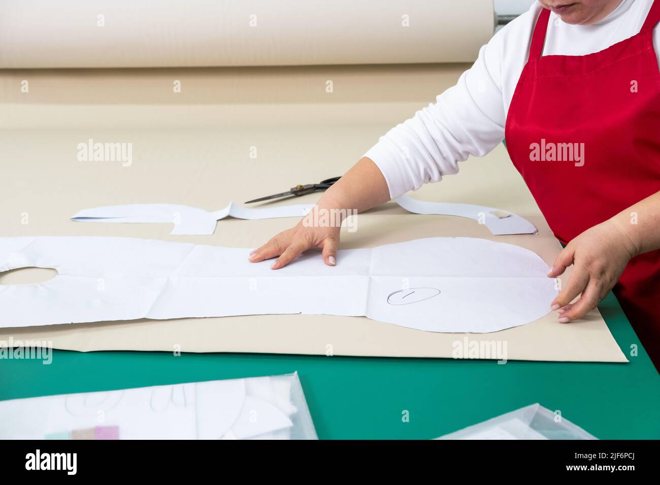 Crop anonymous dressmaker arranging paper patterns on textile while ...
