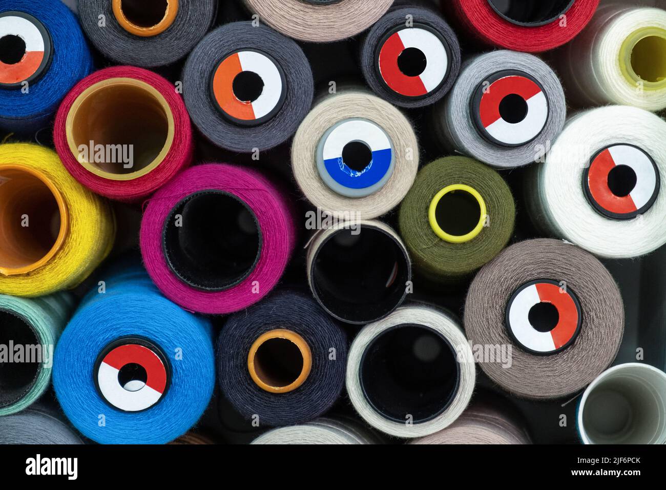 Set of colorful spools of threads for sewing stacked together on white ...