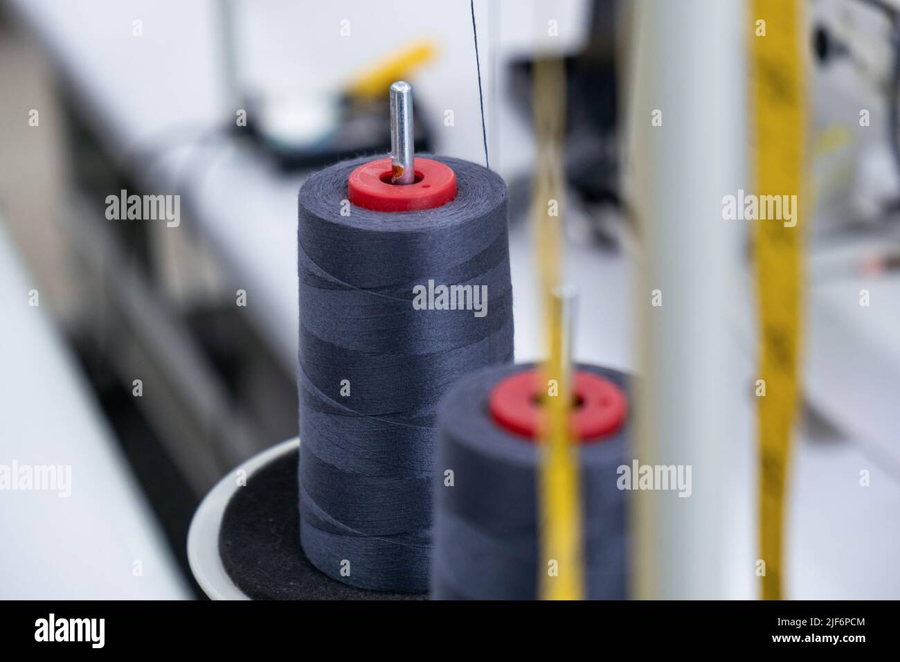 Soft focus spools of dark threads placed on professional sewing machine ...