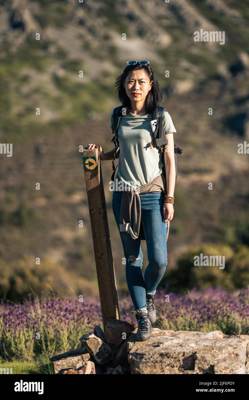 Full body of Asian female hiker looking at camera while standing near ...