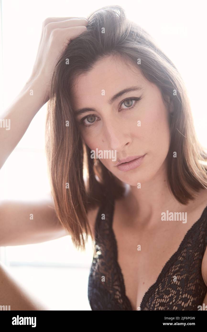 Attractive female model with brown hair looking at camera with sincere face expression with hand ...