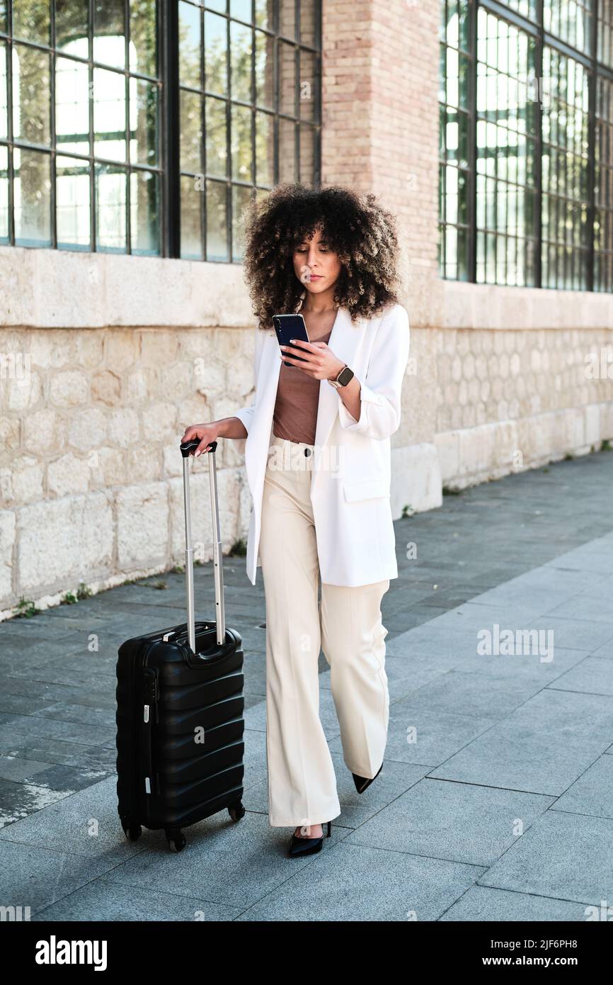 Full length Hispanic female manager in stylish white suit with curly ...