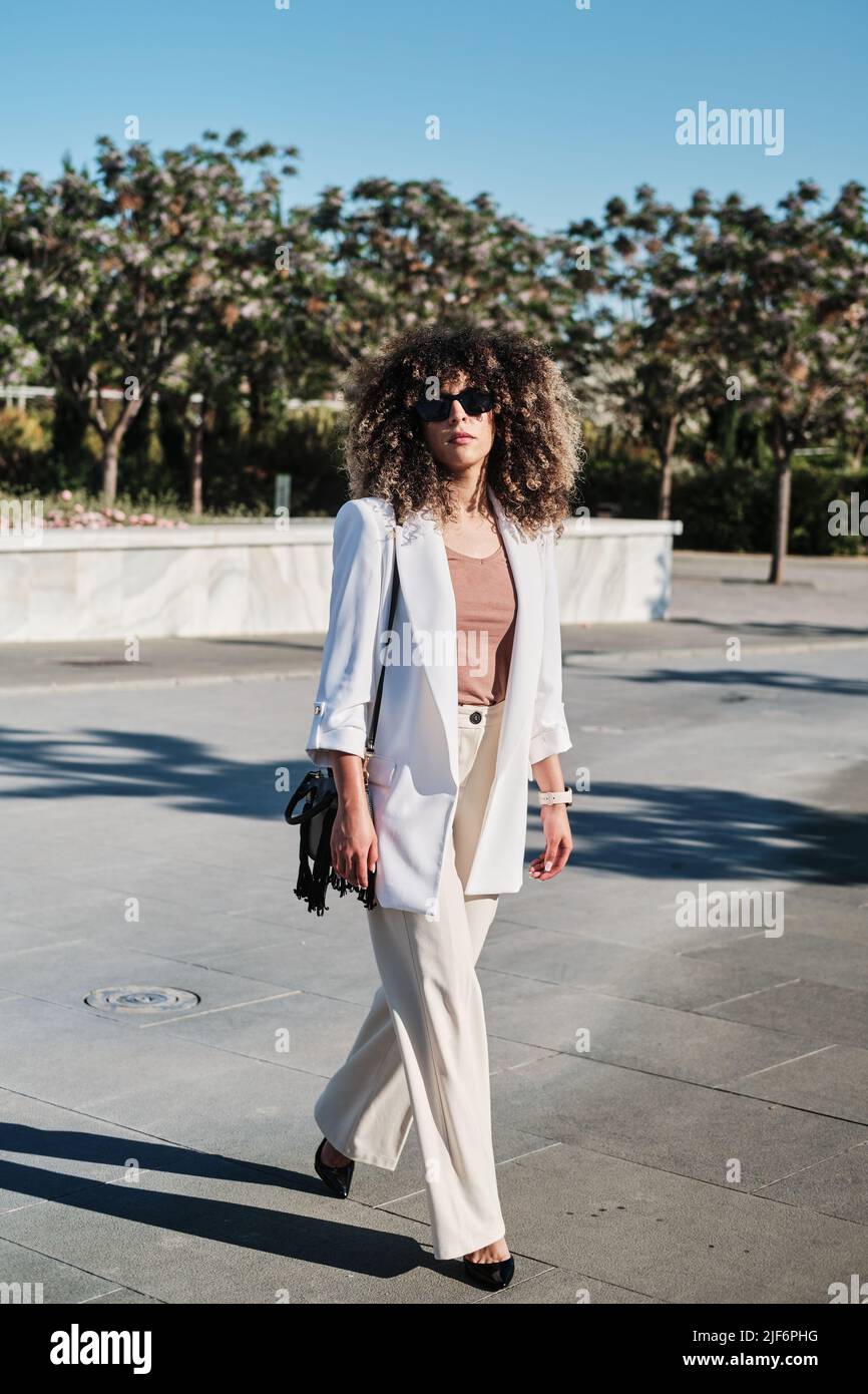 Full body Hispanic female manager in trendy white suit and sunglasses ...
