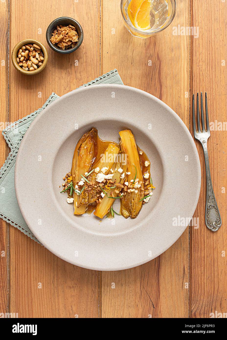 Top view of braised endives with orange juice on a wooden table next to ...