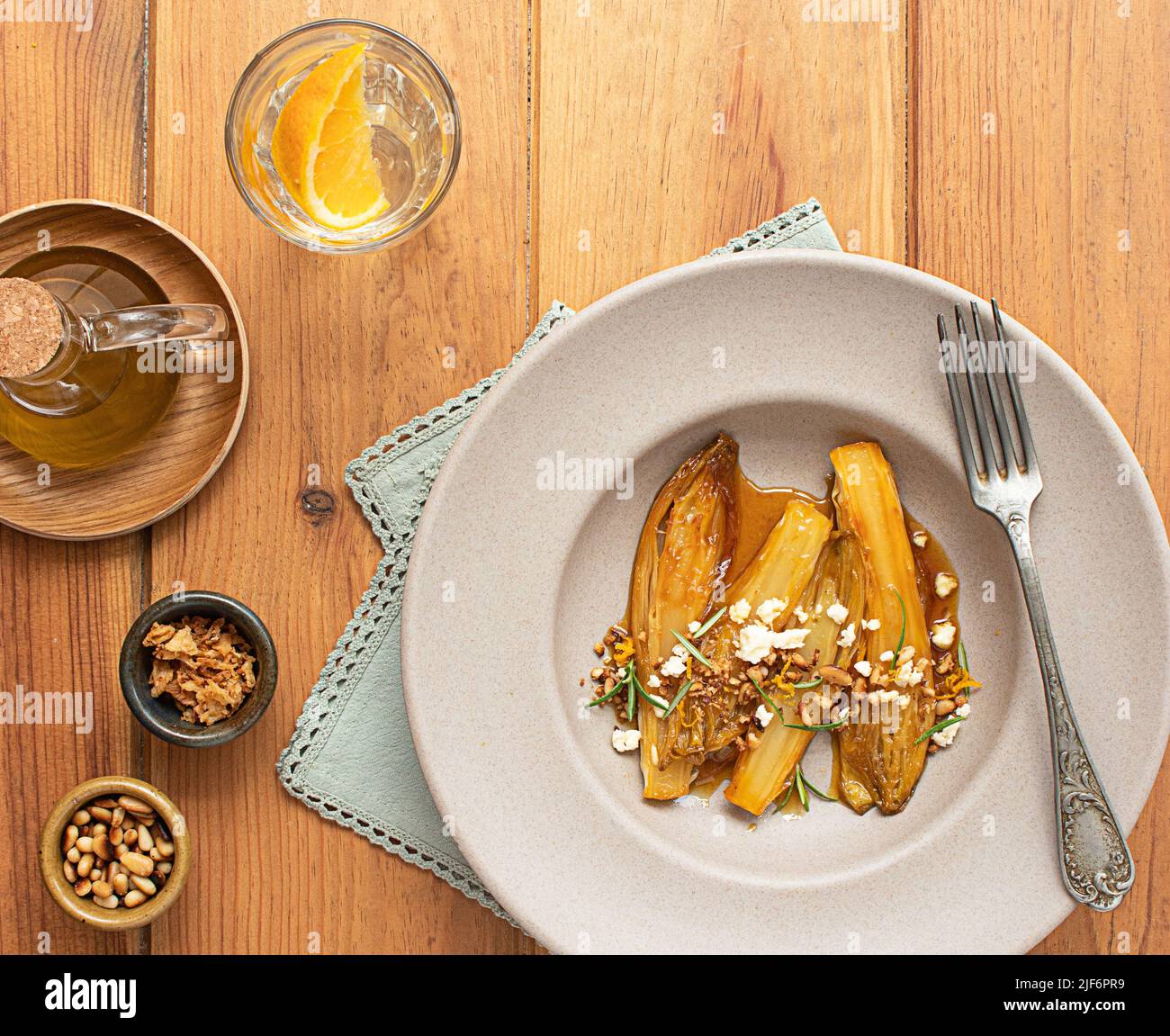 Top view of braised endives with orange juice on a wooden table next to ...