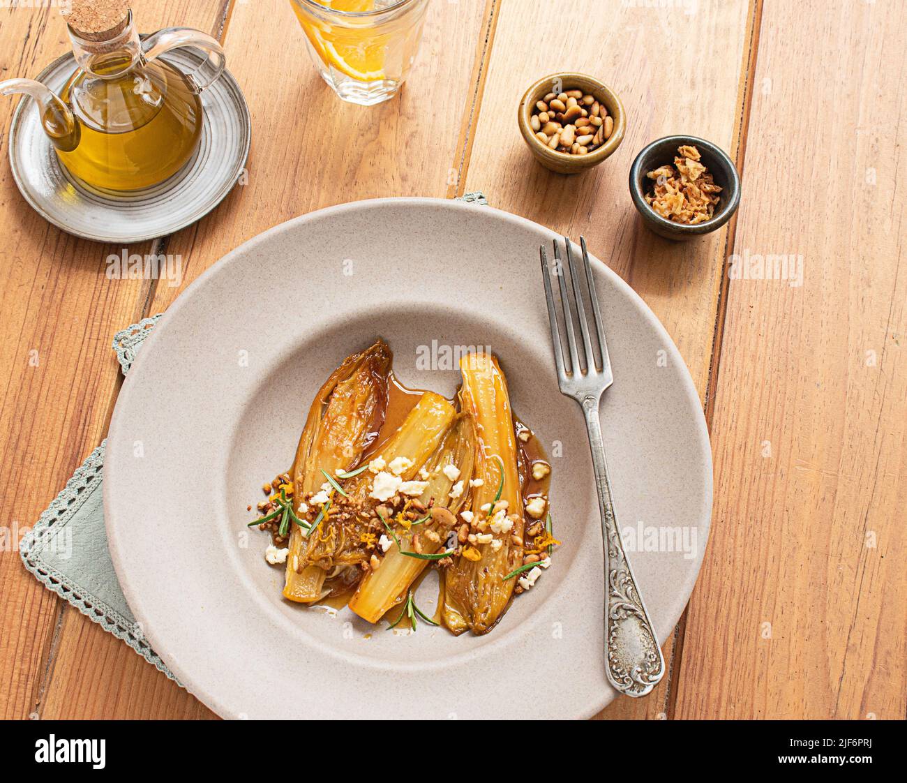 Top view of braised endives with orange juice on a wooden table next to ...