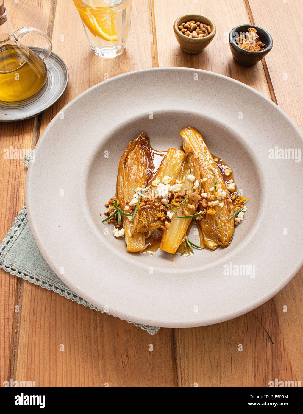 Top view of braised endives with orange juice on a wooden table next to ...