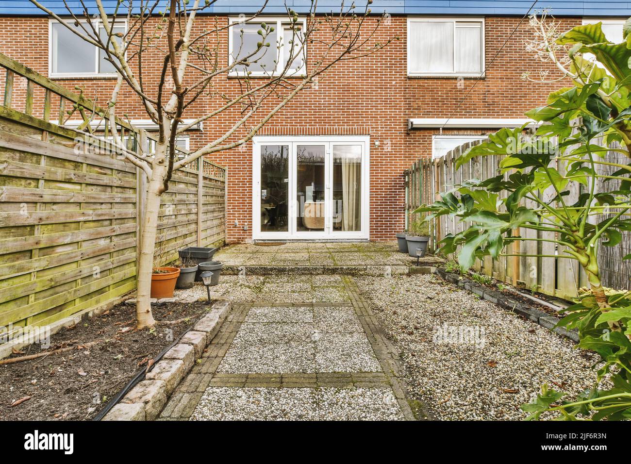 Neat paved patio with sitting area and small garden near wooden fence ...