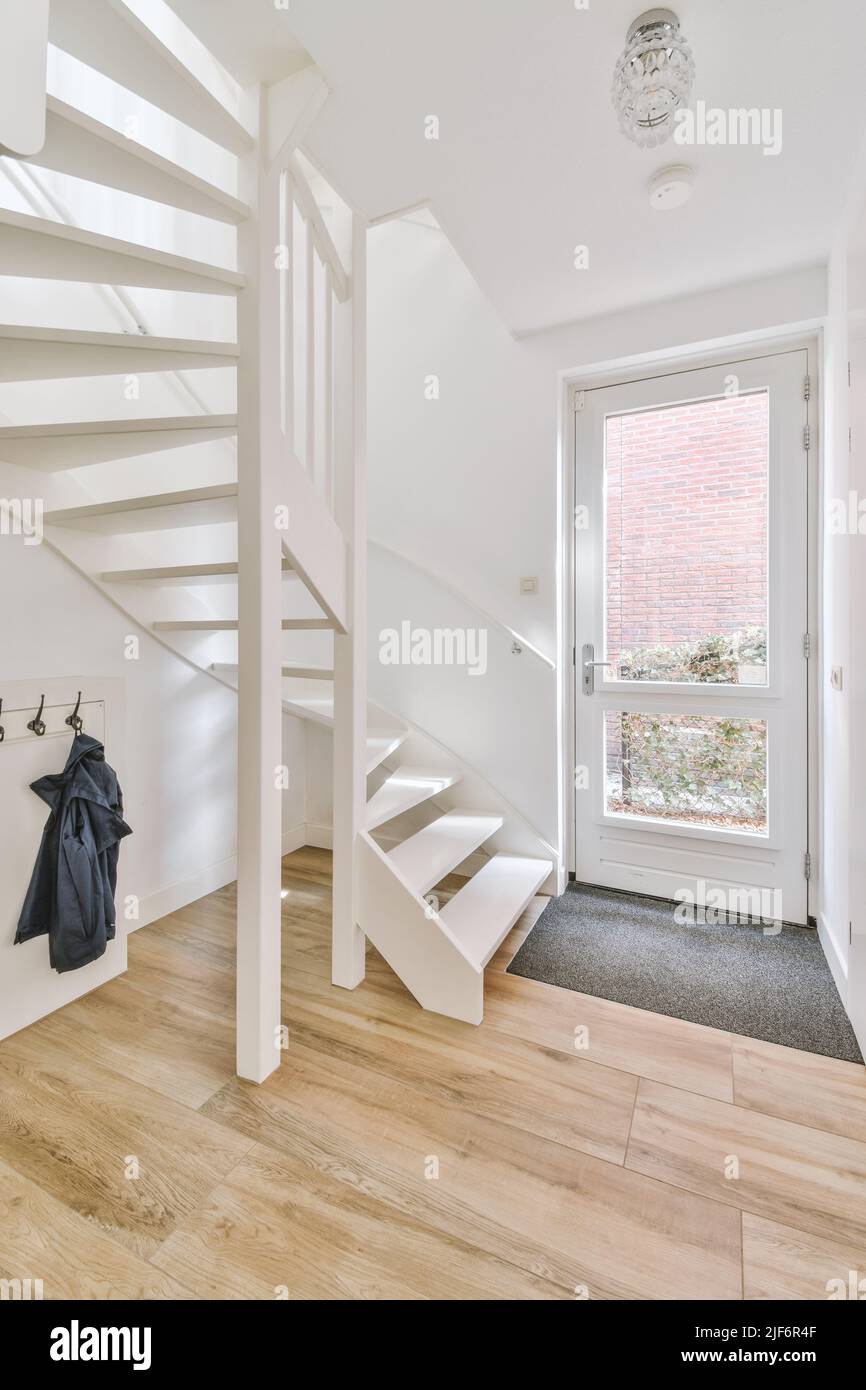 White hallway with wooden stairway leading to second floor of modern ...