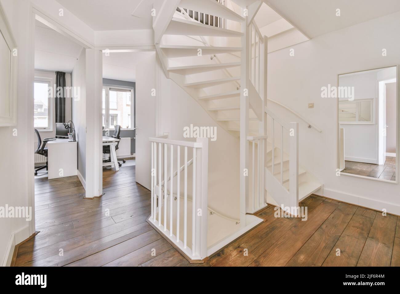 White hallway with wooden stairway leading to second floor of modern ...