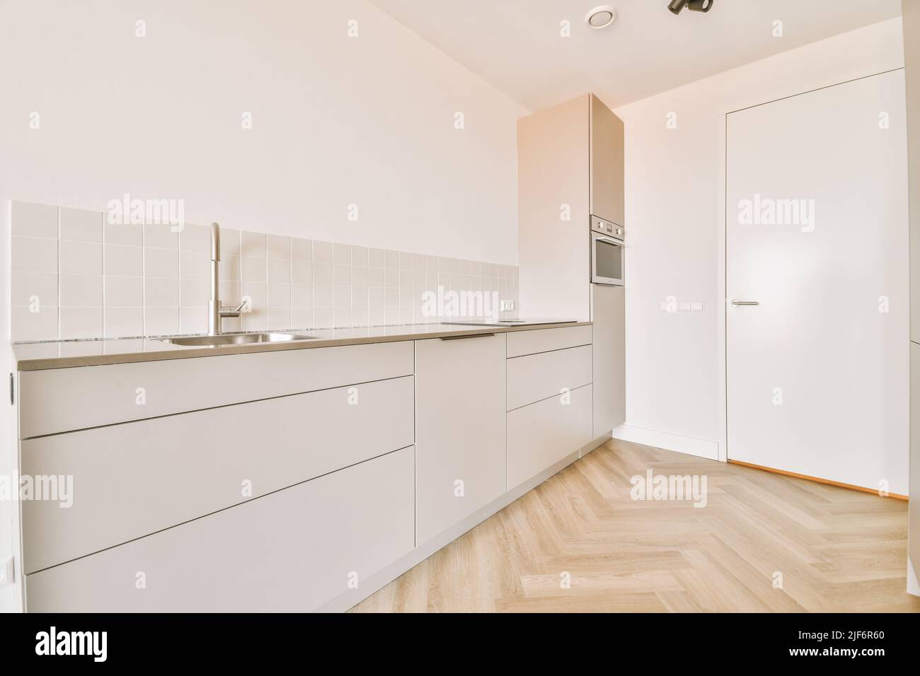 Interior of empty white kitchen with windows and wooden parquet floor ...