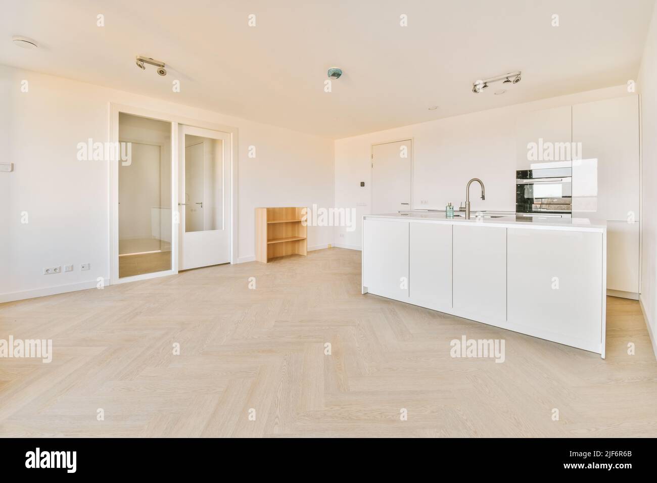 Interior of empty open plan white kitchen and wooden parquet floor ...