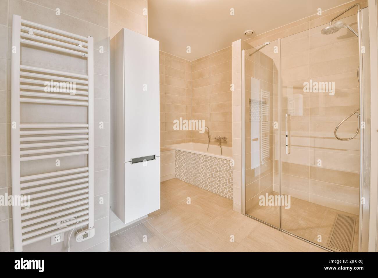 Bathtub located near shower box with glass door in modern bathroom with ...