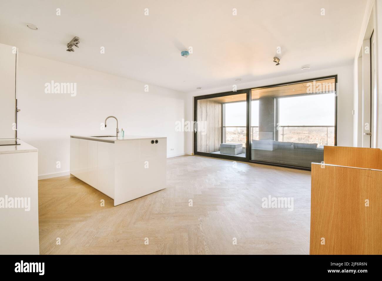 Interior of empty open plan white kitchen with windows and wooden ...