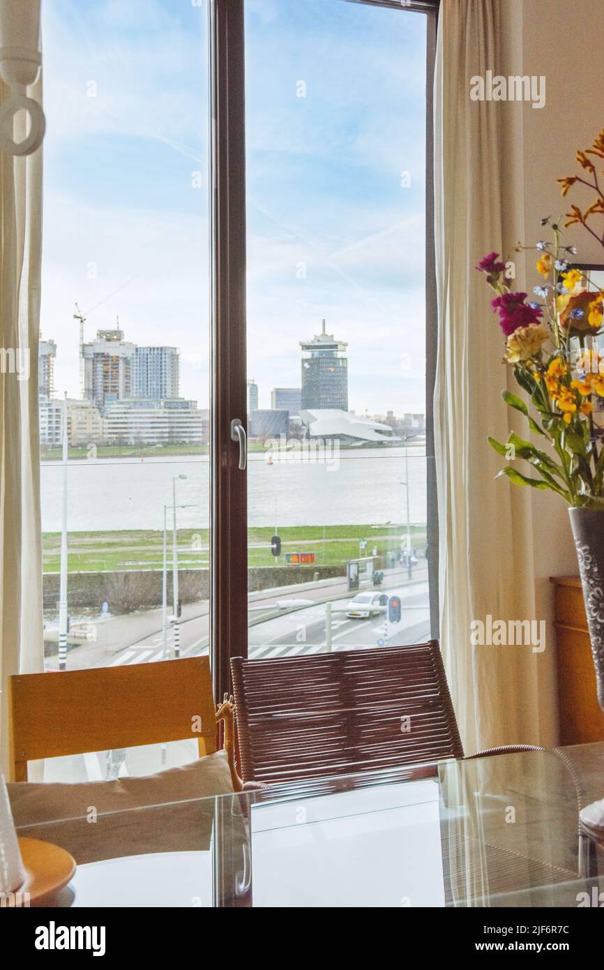 Glass table and chairs located against window with view of city street ...