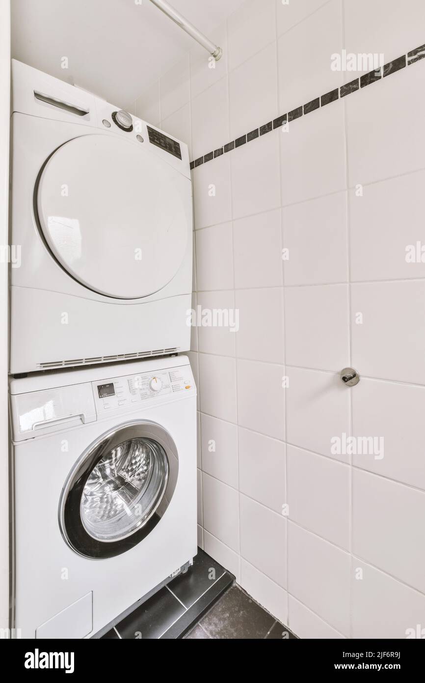 Modern washing and dryer machines placed in light bathroom with white ...