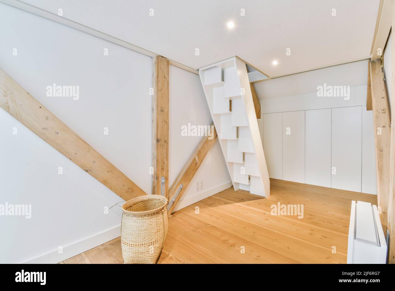 Creative staircase and wicker basket in spacious corridor with wooden ...