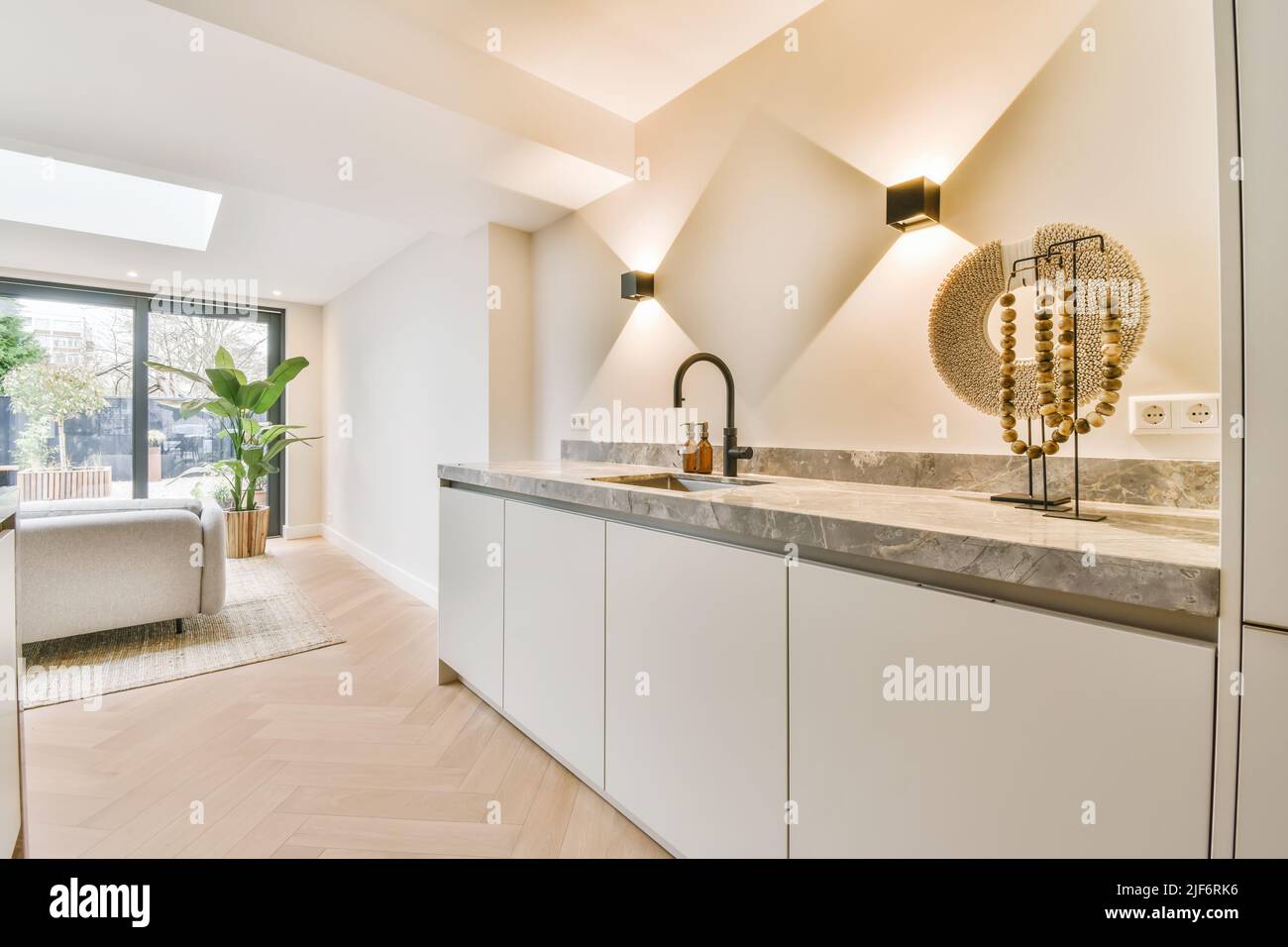 Marble counters with sink at wall with glowing lamps in stylish kitchen ...