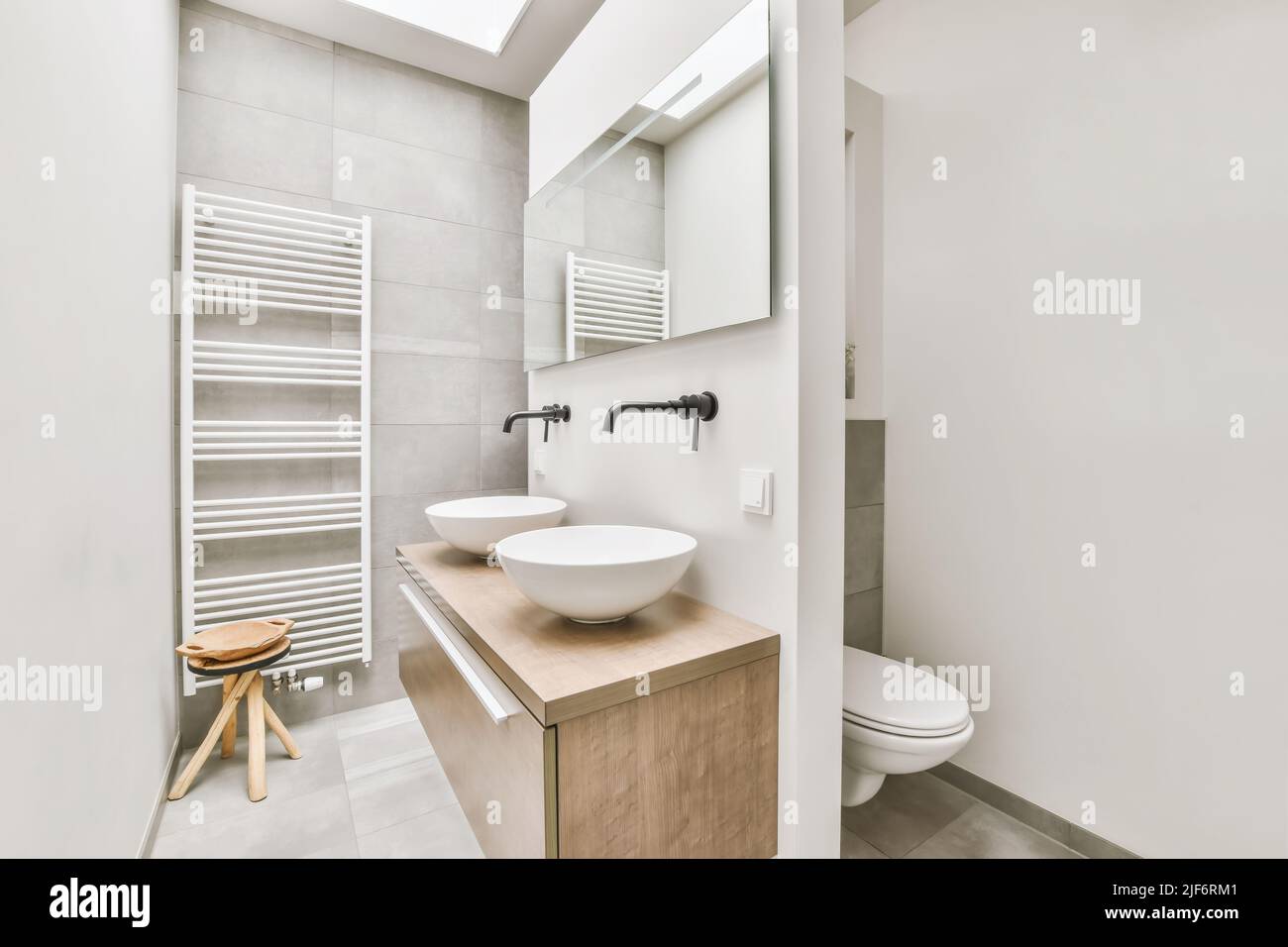 Toilet installed behind partition with sinks and mirror in light ...