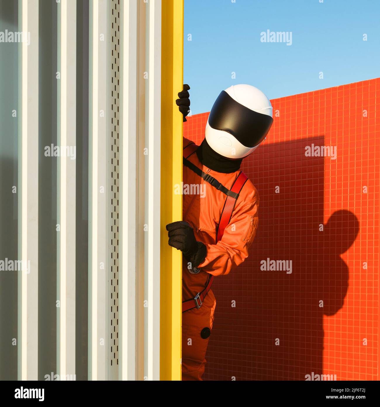 Anonymous cosmonaut in orange spacesuit and futuristic helmet peeking ...