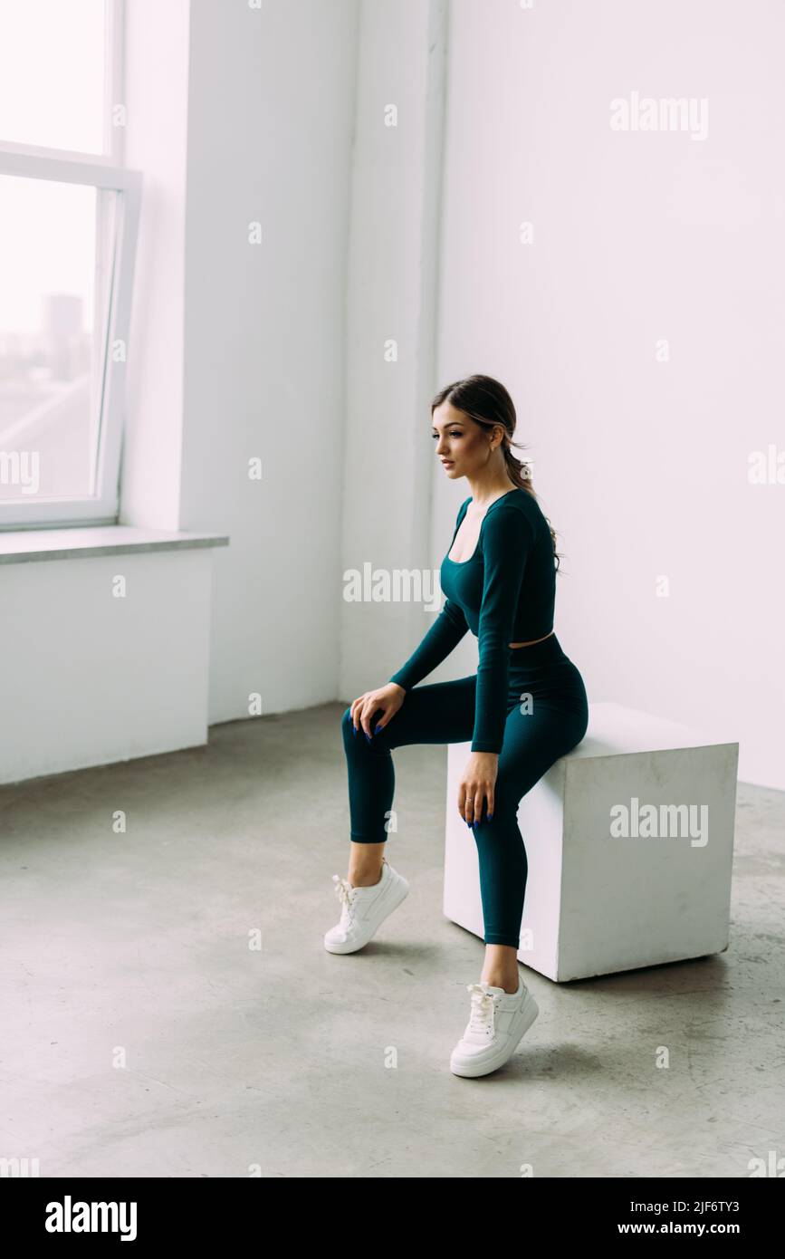 Slim sport woman in sportswear jumping on fit box and do squats ...
