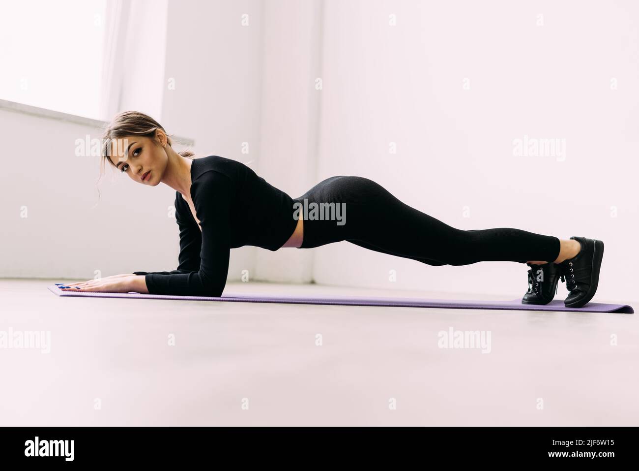 Slim fitnes young girl with ponytail doing planking exercise indoors at ...