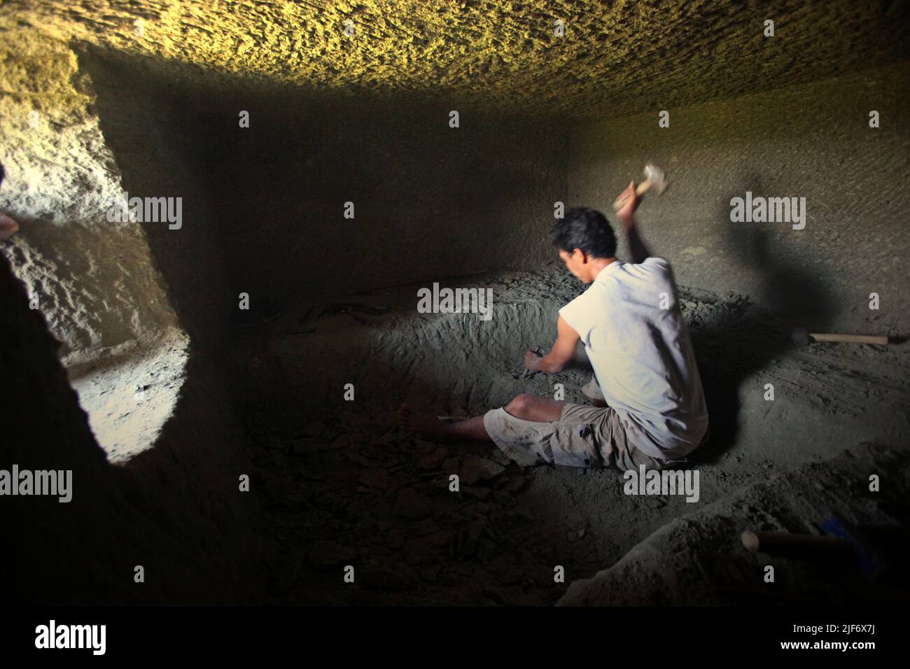 A worker is digging and carving through rock to build a chamber for ...