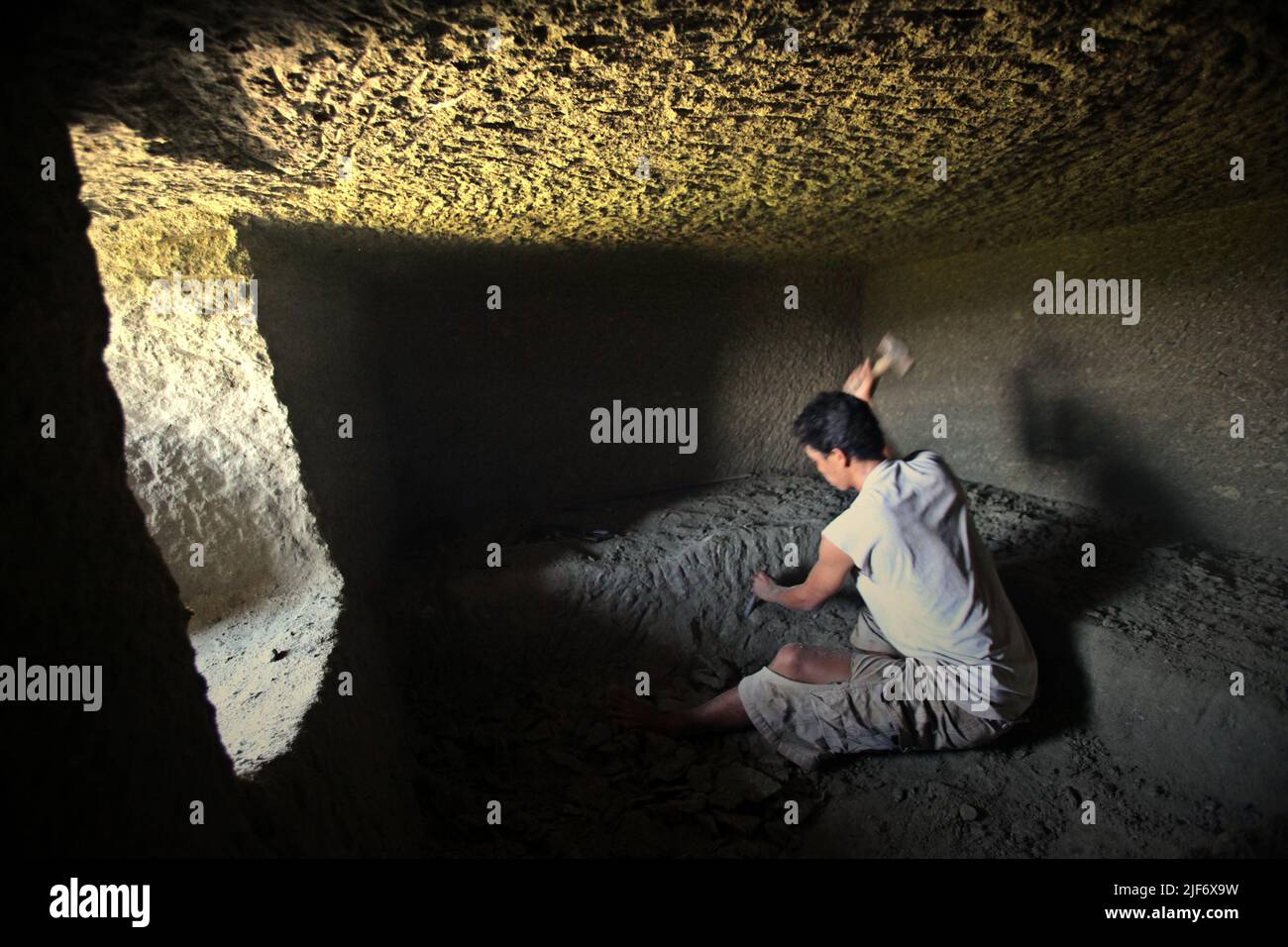 A worker is digging and carving through rock to build a chamber for ...